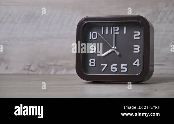 The pointer clock on a wooden table shows the time. Mechanical modern ...