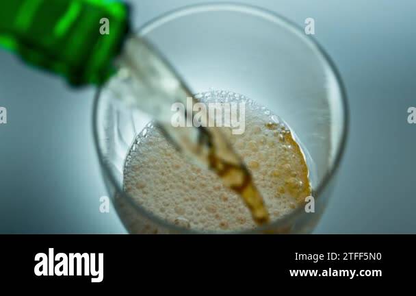 Alcohol liquid jet bubbling into transparent glass top view. Bottle ...