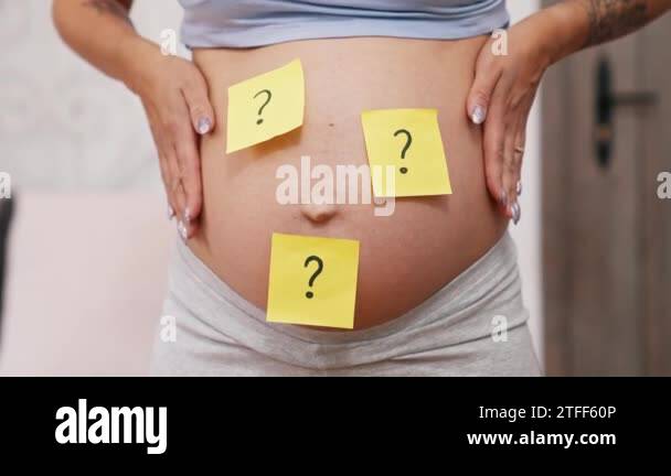 Question mark sticky notes on white pregnant womans belly. Hands on ...