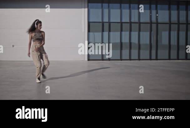 Handheld shot of full body female dancer walking backwards and spinning ...