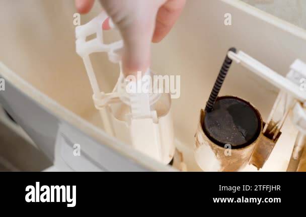 The hand installs the fittings of the toilet bowl flush mechanism into ...