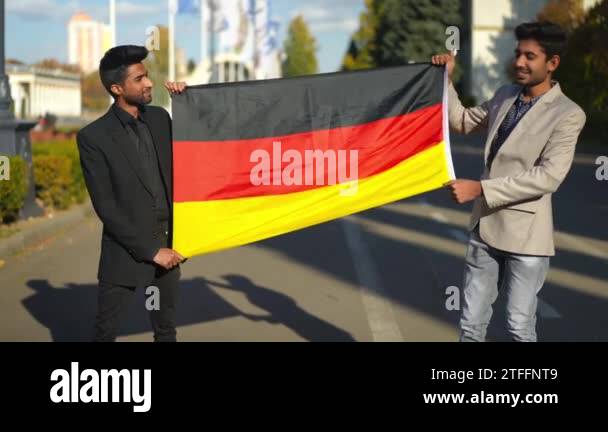 Middle Eastern men in suits stretching German flag standing outdoors ...