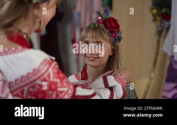 Portrait of cute Ukrainian child smiling looking at woman braiding long ...
