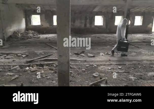 Forensic scientist walks through an abandoned hall with a briefcase to ...