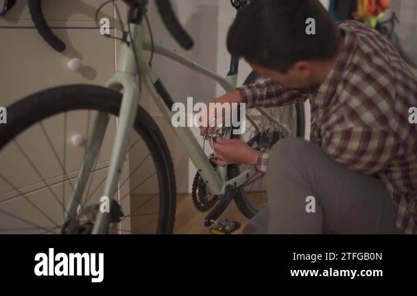 Man is fixing bicycle at home. Male repairs his bike at home. Guy is ...