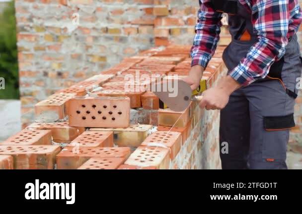 Installing brick wall. Construction worker in uniform and safety ...