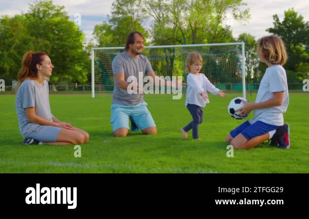 Happy family with two children playing with a soccer ball throwing the ...