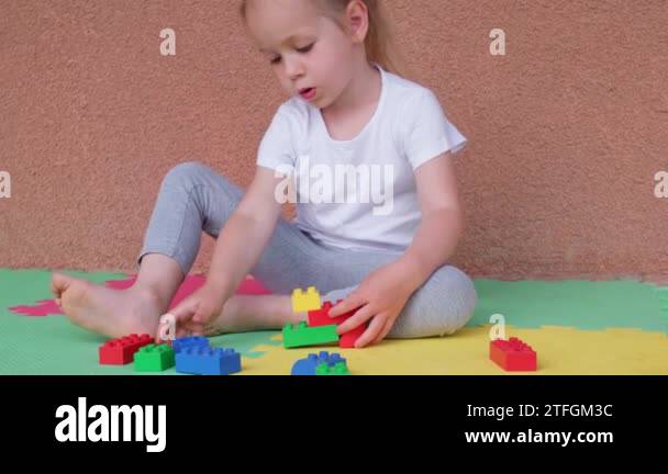 little girl taking apart his lego constructor bricks toys and placed in front Stock Video ...