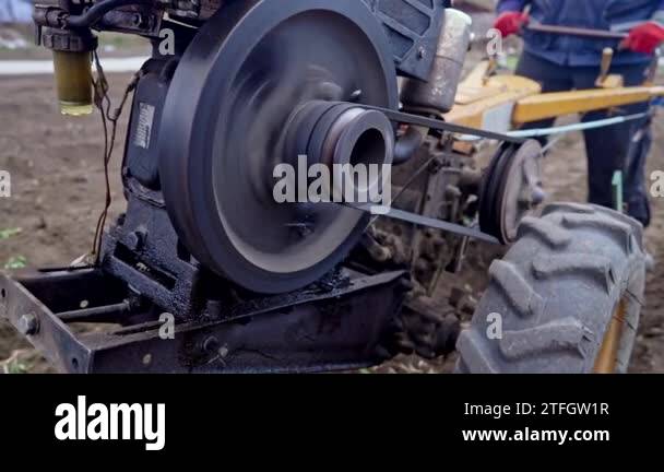 Working process of rotating pulley with belt. Man works in garden with ...