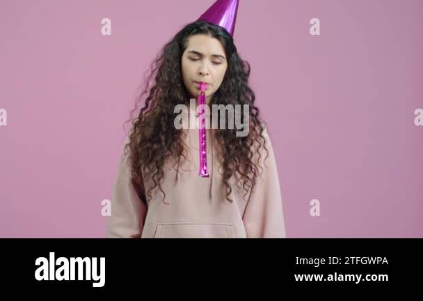 Miserable young woman blowing party horn with sad face then taking off ...