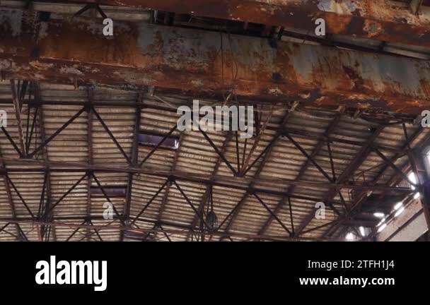 Old rusty metal ceiling in an abandoned factory hangar. Metal beams ...