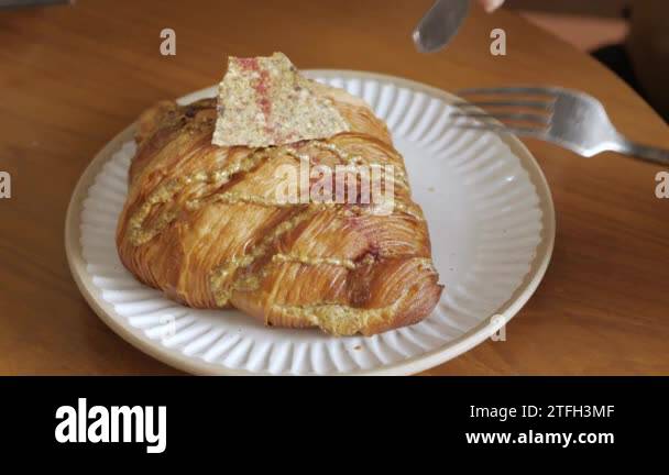 using fork and spoon to cut a fresh baked pistachio croissant bakery ...