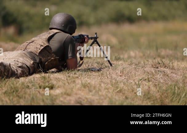 Armed military man unloading machine gun while lying with gun, soldier ...