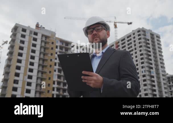 Bearded building inspector wearing hard hat and suit jacket making ...