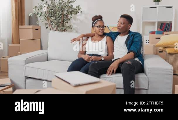 A married couple sits on the couch after moving, embrace each other ...