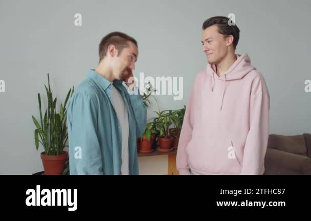 Two lgbt men are standing together in the living room and talking to ...