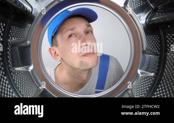Smelly washing machine and laundry room. Master repairman looks inside ...