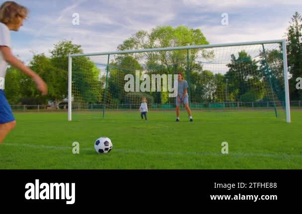 Happy family with two children playing with a soccer ball throwing the ...