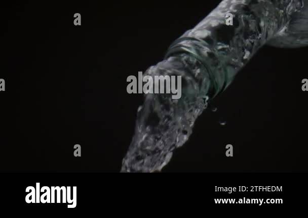 Closeup purified mineral water pouring from glass bottle on black ...
