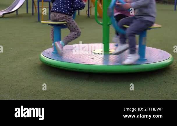 Three little Happy Children having fun spinning on merry-go-round ...