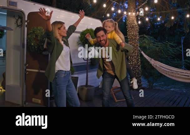 Caucasian family camping outdoors in evening near motor home van ...