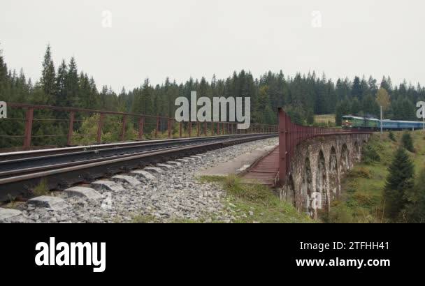 Train goes over the bridge with an old stone viaduct. Train crossing a ...