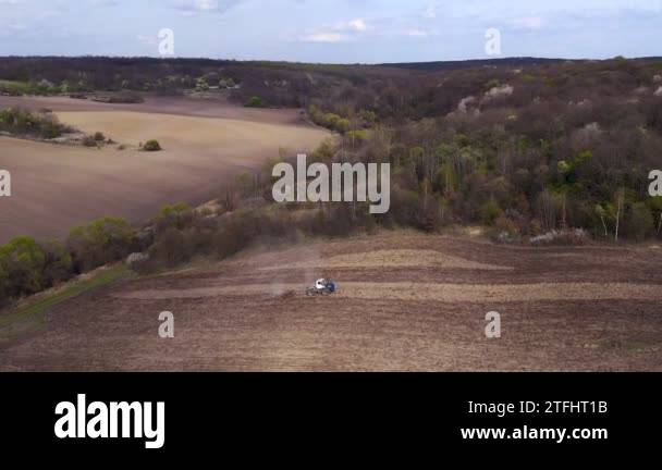 Aerial view large tractor cultivating a dry field. Top down aerial view ...