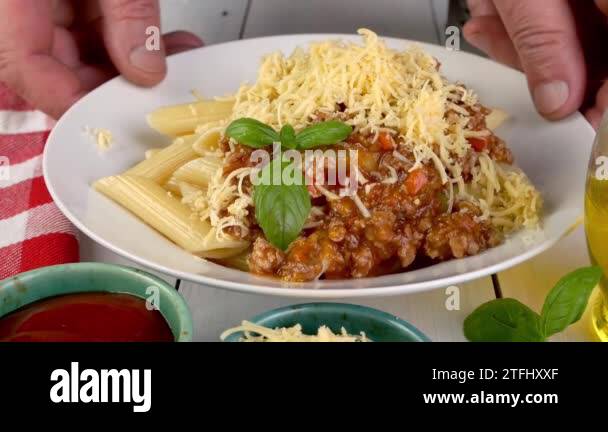 Rotate on table penne pasta with tomato bolognese meat sauce, in white ...