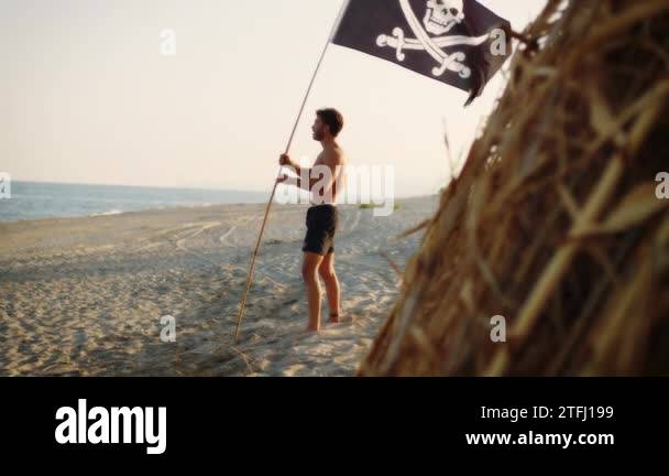 Young boy with pirate flag with skull on the beach on a desert island ...