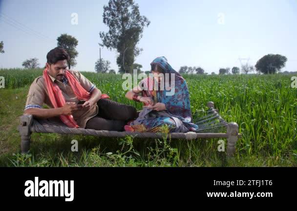 A village couple sitting on a woven cot in the village - modern village ...