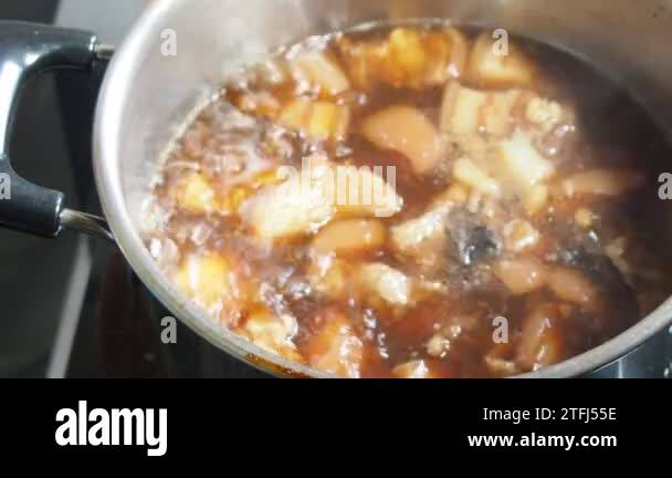 man hand opening pot with Stewed eggs and pork belly. home cooking ...