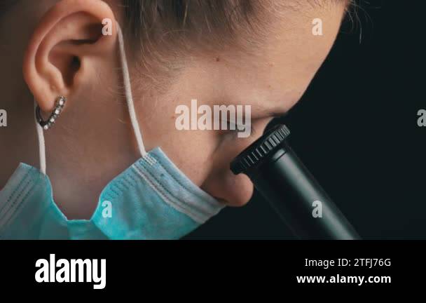 Girl Scientist Looks Into the Lens of a Microscope in a Mask Close-up ...