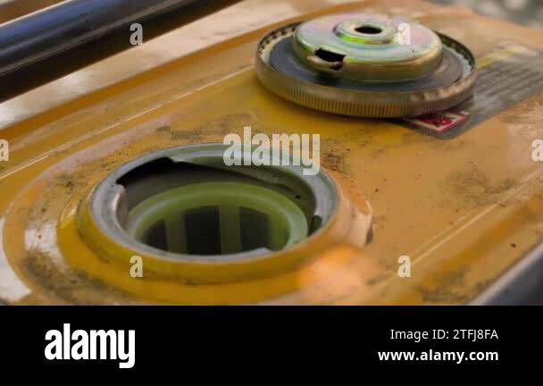 Fuel is poured into the fuel tank of a yellow gas generator from a ...