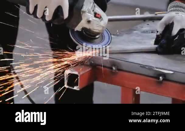Factory Worker Grinds Metal Construction using angle grinder. Bright ...