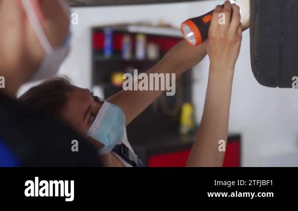 Female mechanic inspecting the car suspension. Strong woman coaching a ...