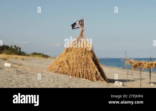 Pirate hut on the beach with black flag with waving skull Stock Video ...