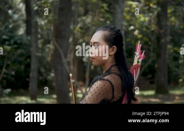 Archery woman chasing an enemy in the jungle with a bow and arrow in ...