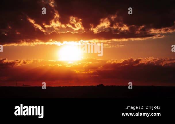 Timelapse of epic sunset in the orange sky through layered clouds. The ...