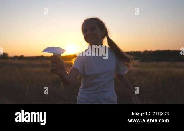 Happy small girl running with paper airplane through grass field ...