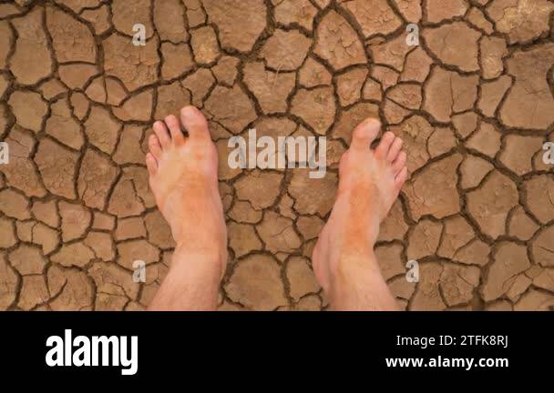 POINT OF VIEW: First person view of bare feet on a cracked desert ...