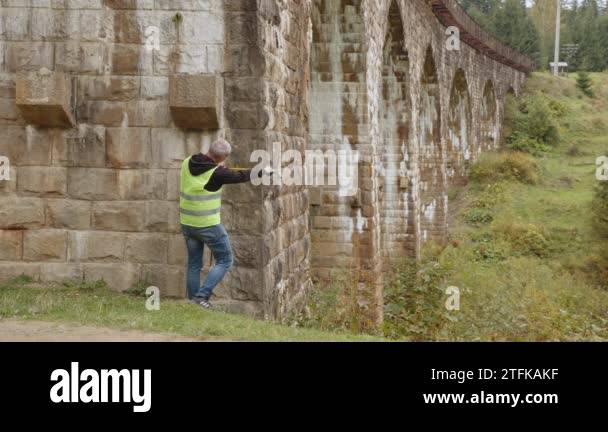 Inspection of bridges. A senior gray-haired engineer stands under a ...