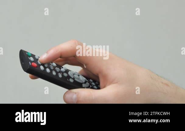 Male hand with remote pressing the TV button and changing, switching ...
