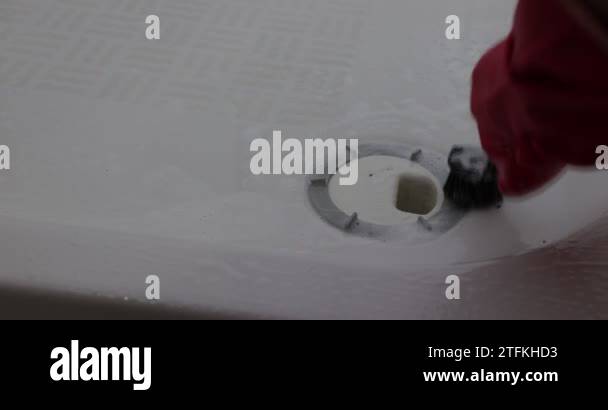Hands with red gloves scrubbing and unclogging dirty shower drain, for ...