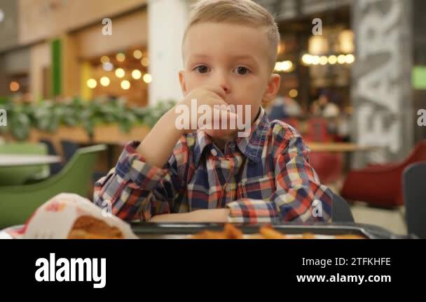 Caucasian boy satisfies his hunger by eating potatoes in a rustic way ...