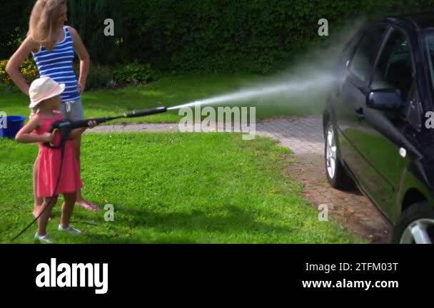 Mother and five years old daughter washing car with high pressure ...
