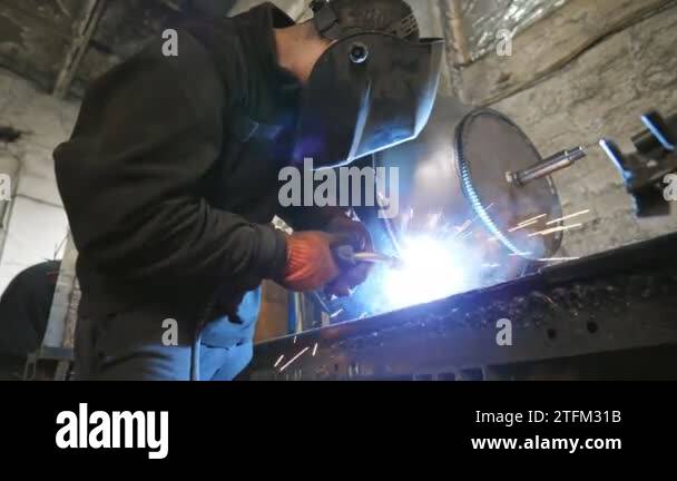 Worker welding parts of the metal detail together. Welder doing joint ...