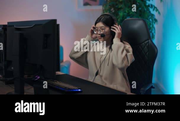 Popular girl streamer walks into room lit by led lights, sits down on ...