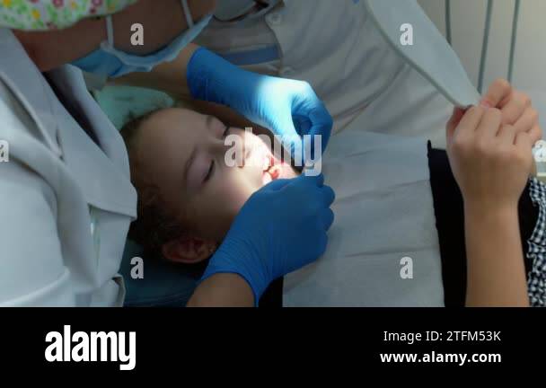 Dentist before removal,winds dental floss on milk tooth little girl ...
