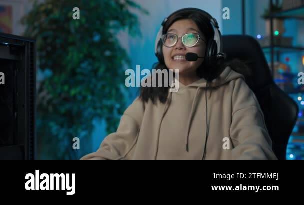 Young Asian girl in nerd glasses professional gamer, wearing headset ...