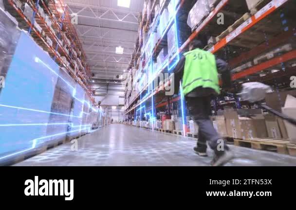 A worker is carrying a rokla through a large warehouse. The worker ...